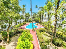 Resort com piscina, palmeiras e um caminho vermelho.