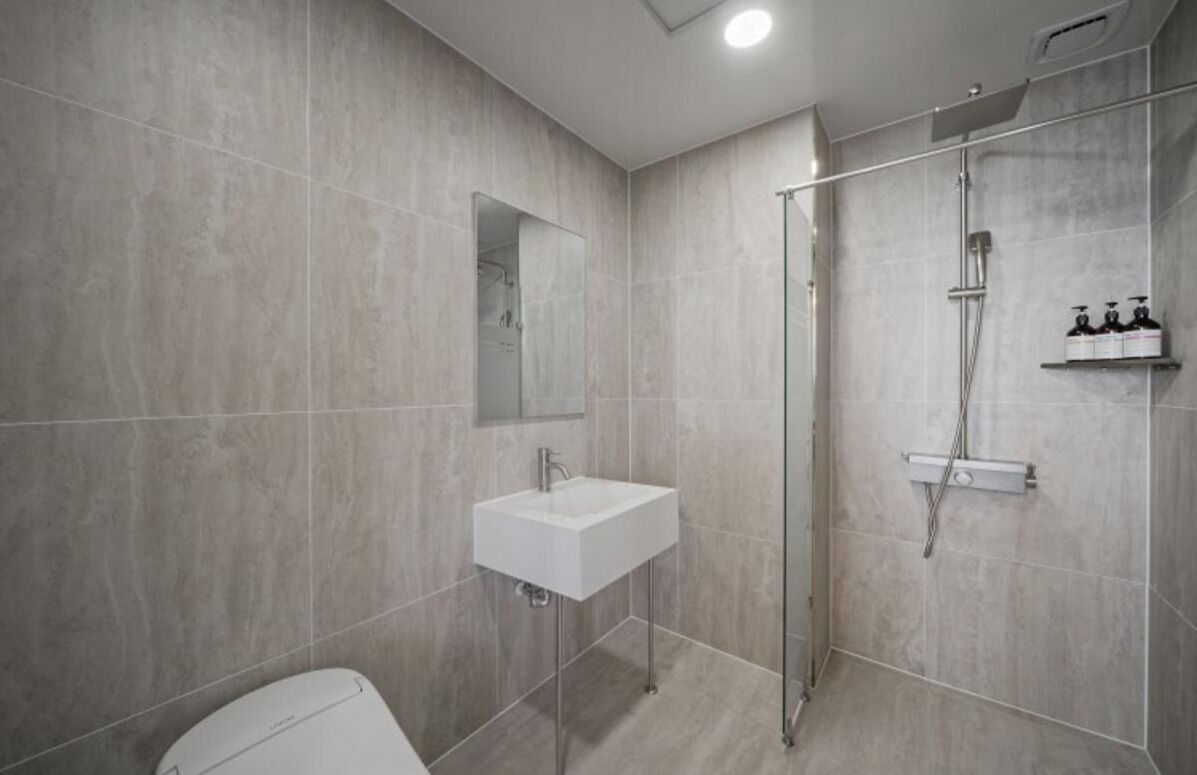 Uma casa de banho moderna com chuveiro envidraçado, lavatório branco e espelho.