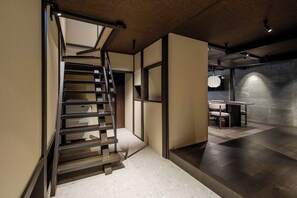Um interior moderno com uma escada em espiral, uma área de jantar com mesa e cadeiras, e uma cozinha com um lustre.