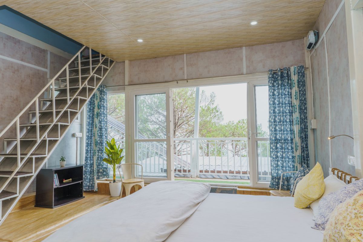 Quarto com uma cama grande, escada e vista para o exterior.