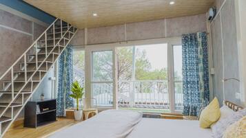 Quarto com uma cama grande, escada e vista para o exterior.