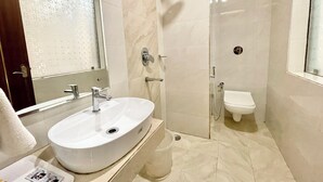 Um banheiro com pia branca, vaso sanitário e chuveiro.