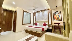 Quarto de hotel com cama, escrivaninha, cadeira e ventoinha no teto.