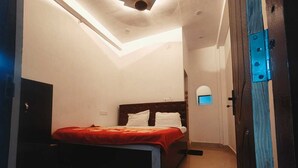 Quarto com cama, TV, claraboia e porta com puxador azul.