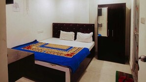 Quarto com cama, mesa de cabeceira, ventilador de teto, aparelho de ar condicionado e uma porta.