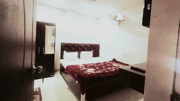 Quarto com cama, mesa de cabeceira, espelho e porta.