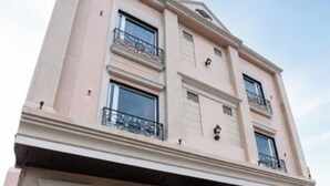 Um edifício de vários andares com fachada simétrica, entrada central com porta e uma pequena varanda no andar superior.