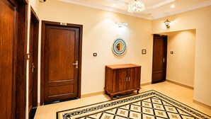 Um corredor com portas de madeira, um armário central e um tapete estampado.