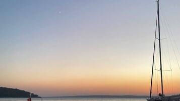 Uma marina com barcos atracados, céu claro e mar calmo.