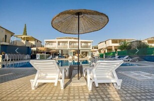 Área de piscina com espreguiçadeiras e um grande guarda-sol.
