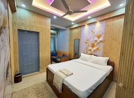 Quarto com cama, ventilador de teto, porta de madeira e parede com desenho floral.