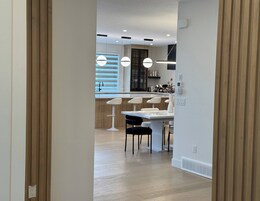 Cozinha moderna com área de refeições, piso de madeira e iluminação pendente.