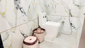 Casa de banho com sanita, bidé e duas caixas de lixo.