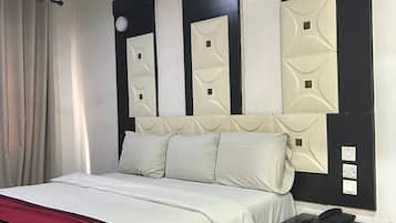 Quarto com cama, mesa de cabeceira, telefone e ventoinha no teto.