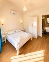Quarto com cama, mesas de cabeceira, guarda-roupa e ar condicionado.