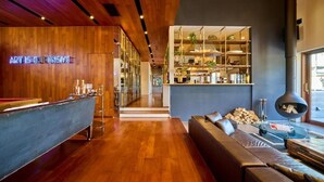 Um interior moderno com mesa de bilhar, letreiro de neon, bar e área de estar com lareira.