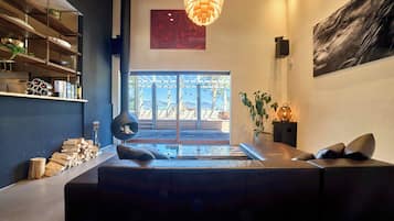 Uma sala de estar moderna com um sofá seccional, lareira, uma janela grande com vista e um lustre.