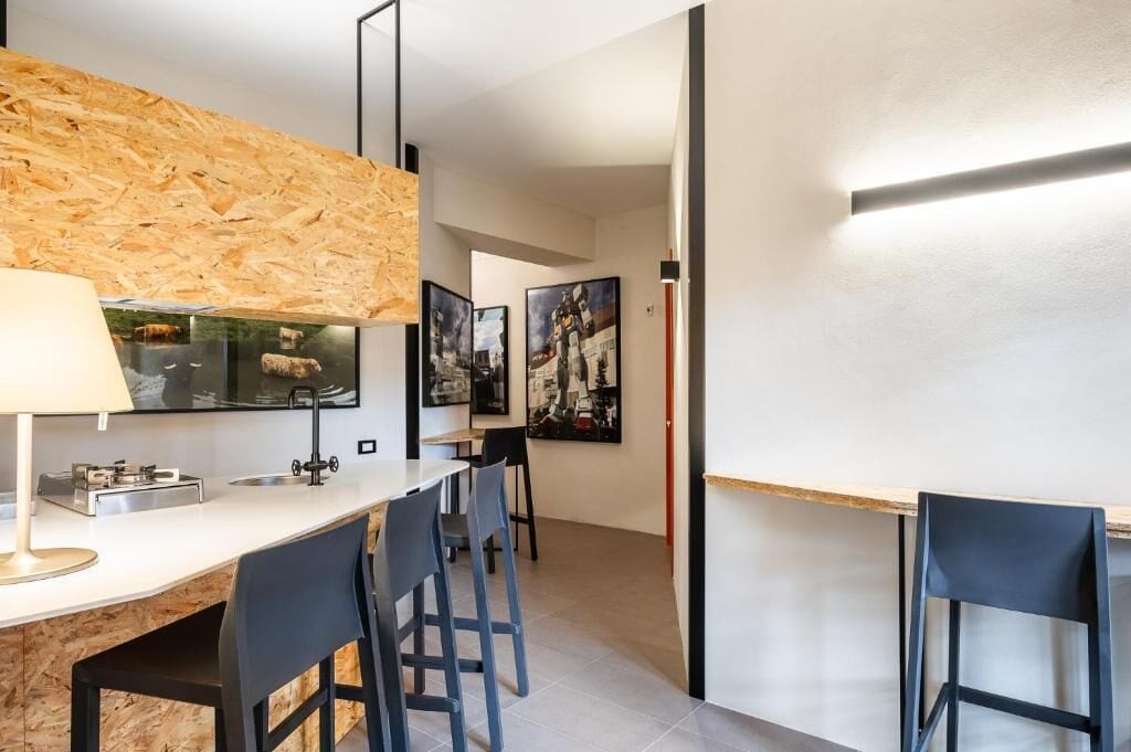 Uma cozinha moderna com painel de parede de madeira, fogão embutido e pia. Há três cadeiras e uma mesa.
