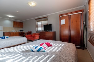 Quarto de hotel com duas camas, televisão, secretária com computador e guarda-roupa.