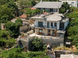 Um edifício de dois andares com fachada de pedra, várias varandas e áreas de estar ao ar livre.