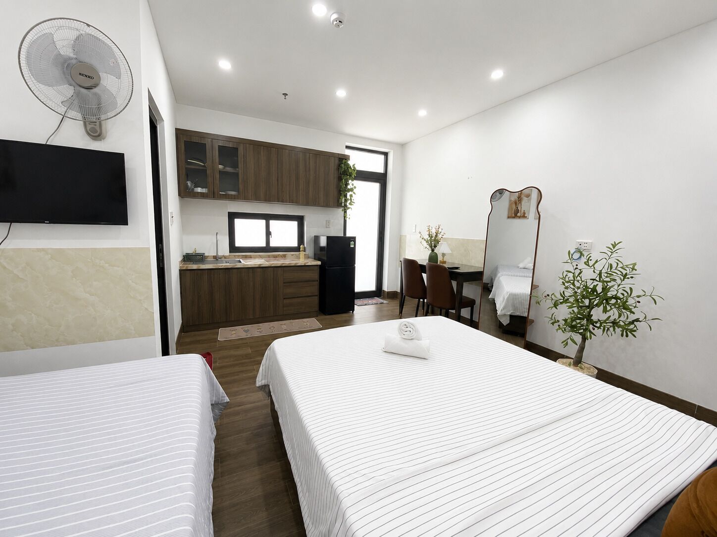 Quarto de hotel com duas camas, uma cozinha compacta, área de refeições e banheiro.