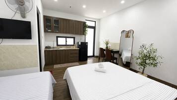 Quarto de hotel com duas camas, uma cozinha compacta, área de refeições e banheiro.