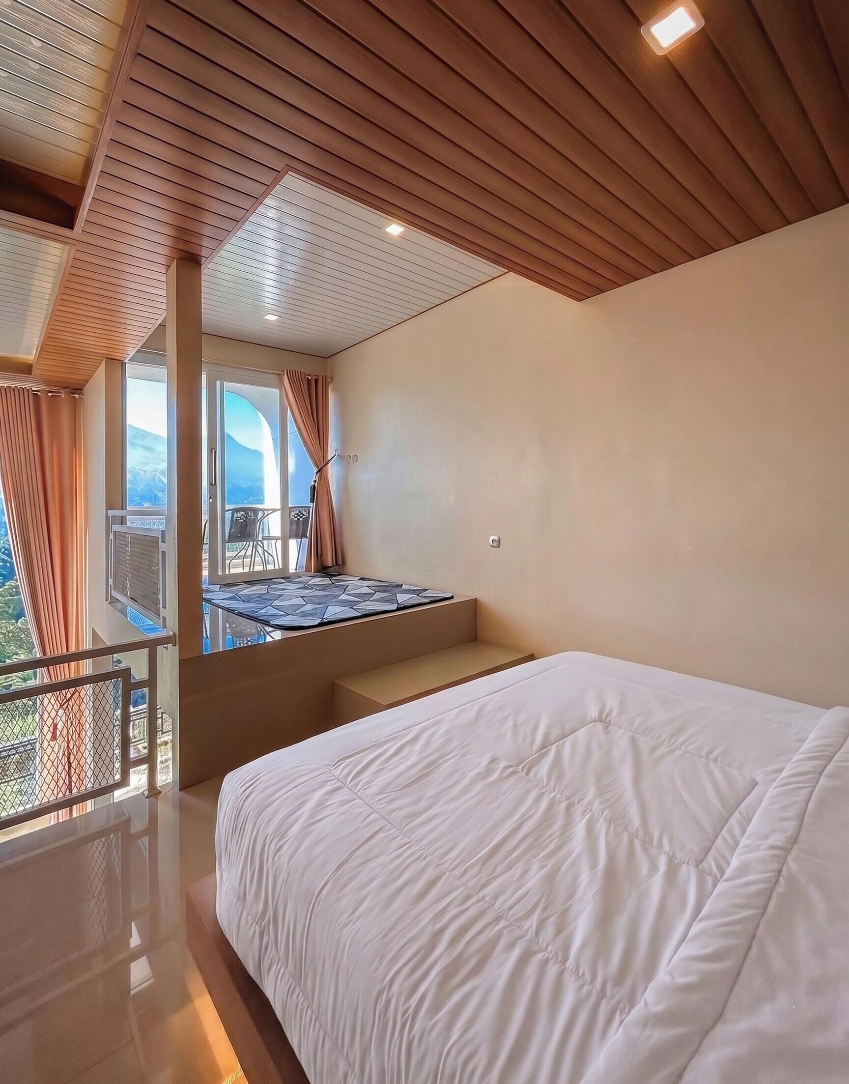 Quarto com uma cama grande, varanda e vista, e teto de madeira.