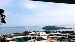Vista costeira com edifícios, um corpo de água e uma ilha ao longe.
