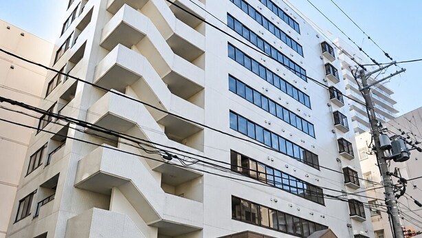 Um edifício com vários andares, fachada plana, diversas varandas e uma placa indicando que é um hotel.