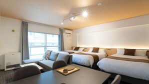 Quarto de hotel com duas camas, uma mesa e uma janela.