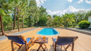 Uma área à beira da piscina com espreguiçadeiras e um deck de madeira.