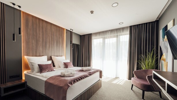 Quarto de hotel moderno com uma cama grande, uma escrivaninha e uma televisão.