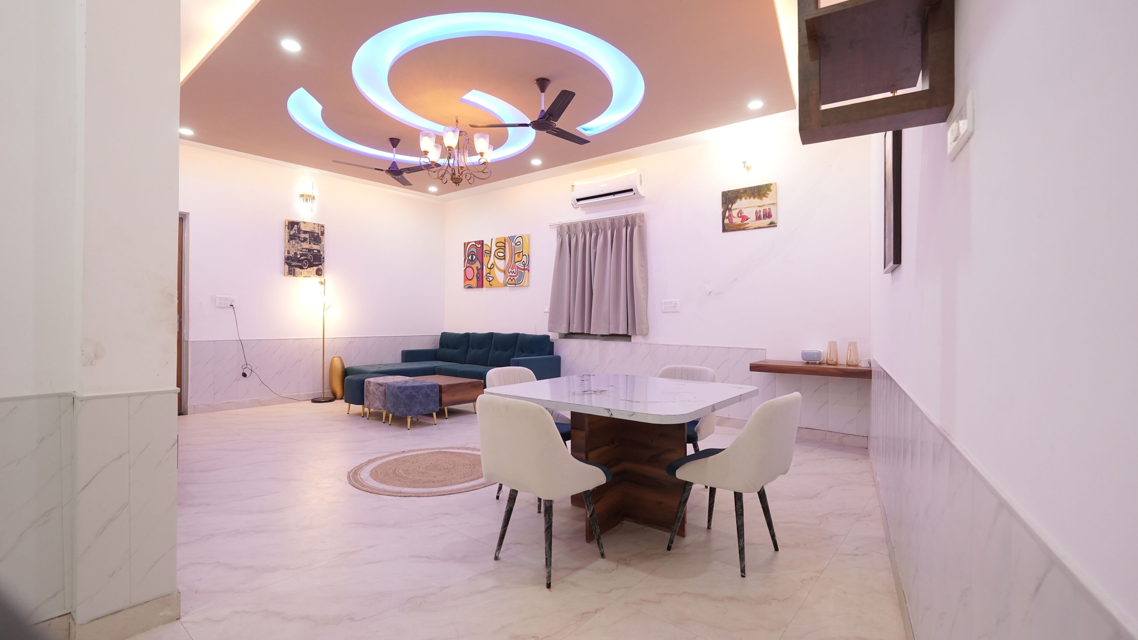 Uma sala moderna com área de jantar, ventilador de teto e lustre.