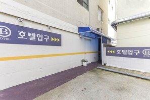 Entrada de hotel com placas de sinalização e toldo azul.