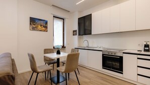 Uma cozinha moderna com armários brancos, forno embutido e um espaço de jantar com mesa e cadeiras.