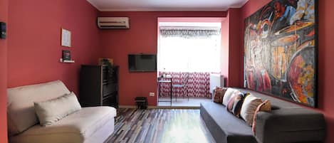 Uma sala de estar com um sofá, uma televisão e um quadro na parede.
