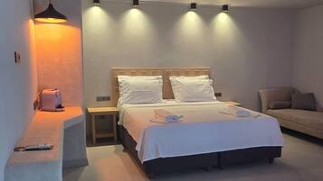 Quarto moderno com cama, mesas de cabeceira, um banco e um sofá.