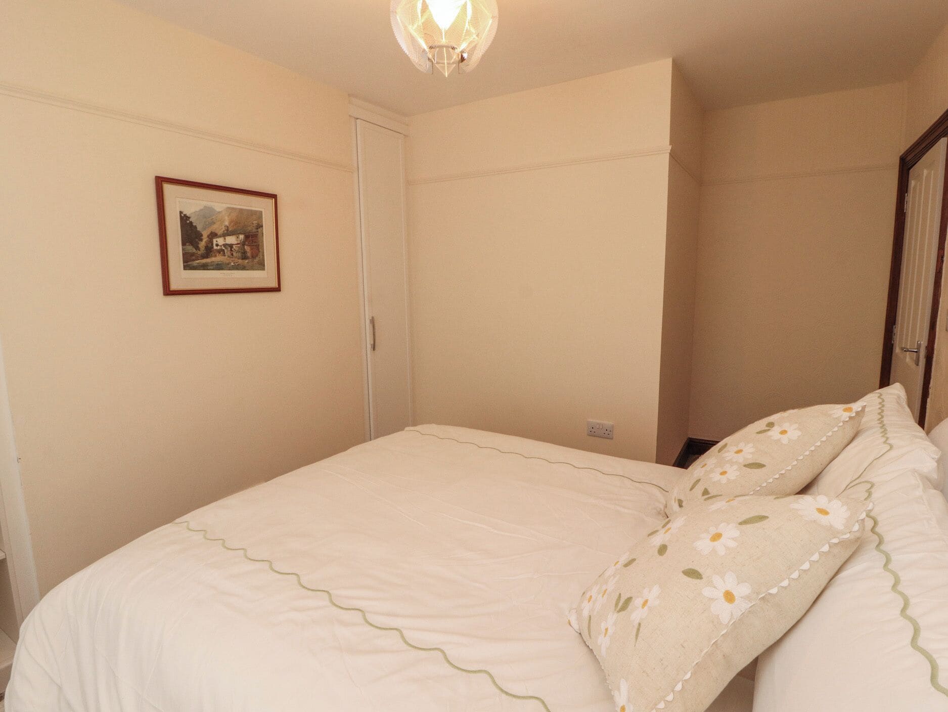 Um quarto com uma cama, um quadro na parede e uma porta.