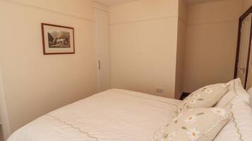 Um quarto com uma cama, um quadro na parede e uma porta.