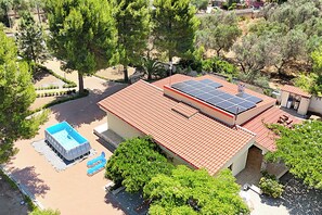 Um imóvel residencial com piscina, painéis solares e telhado de telhas vermelhas.