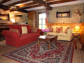 Uma sala de estar acolhedora com um sofá vermelho, um sofá bege, uma mesa de centro de madeira e um tapete estampado.