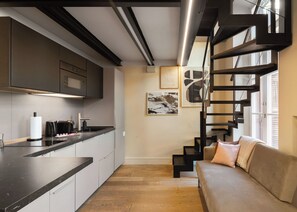 Uma cozinha moderna com bancada preta, eletrodomésticos de aço inoxidável e piso de madeira.