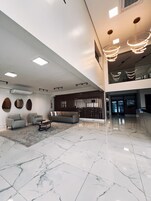Um hall amplo com piso de mármore, mobiliário moderno e luminárias contemporâneas.