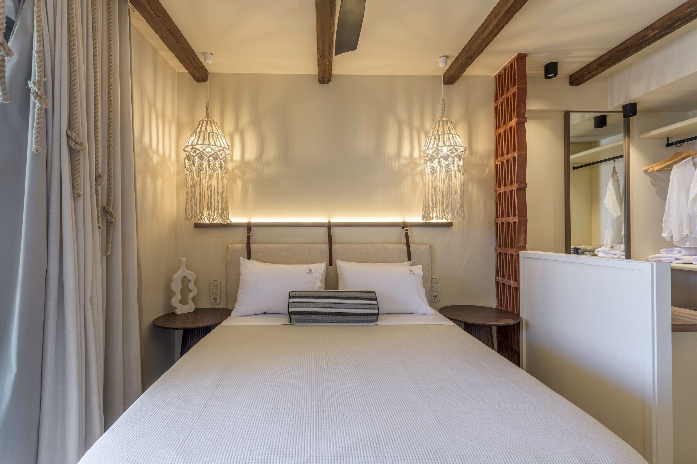 Quarto de hotel com uma cama grande, duas mesas de cabeceira, um espelho e um guarda-roupa.