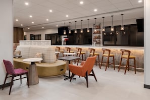 Uma área de estar moderna com sofás, uma máquina de café e um balcão de bar.