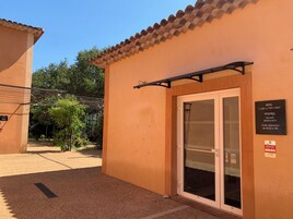 Entrada de hotel com telhado de azulejos, porta de vidro e placa indicando quartos disponíveis.