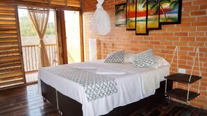 Quarto com uma cama, uma cadeira suspensa e vista por uma porta.