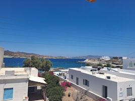 Zona residencial costeira com edifícios, céu azul límpido e vista para o mar.