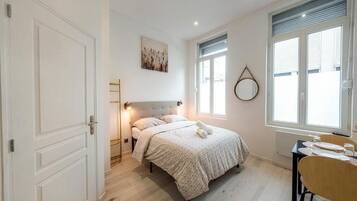 Quarto com cama, mesa de cabeceira e janela.