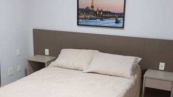 Quarto com uma cama, duas mesas de cabeceira e uma imagem da Torre Eiffel na parede.